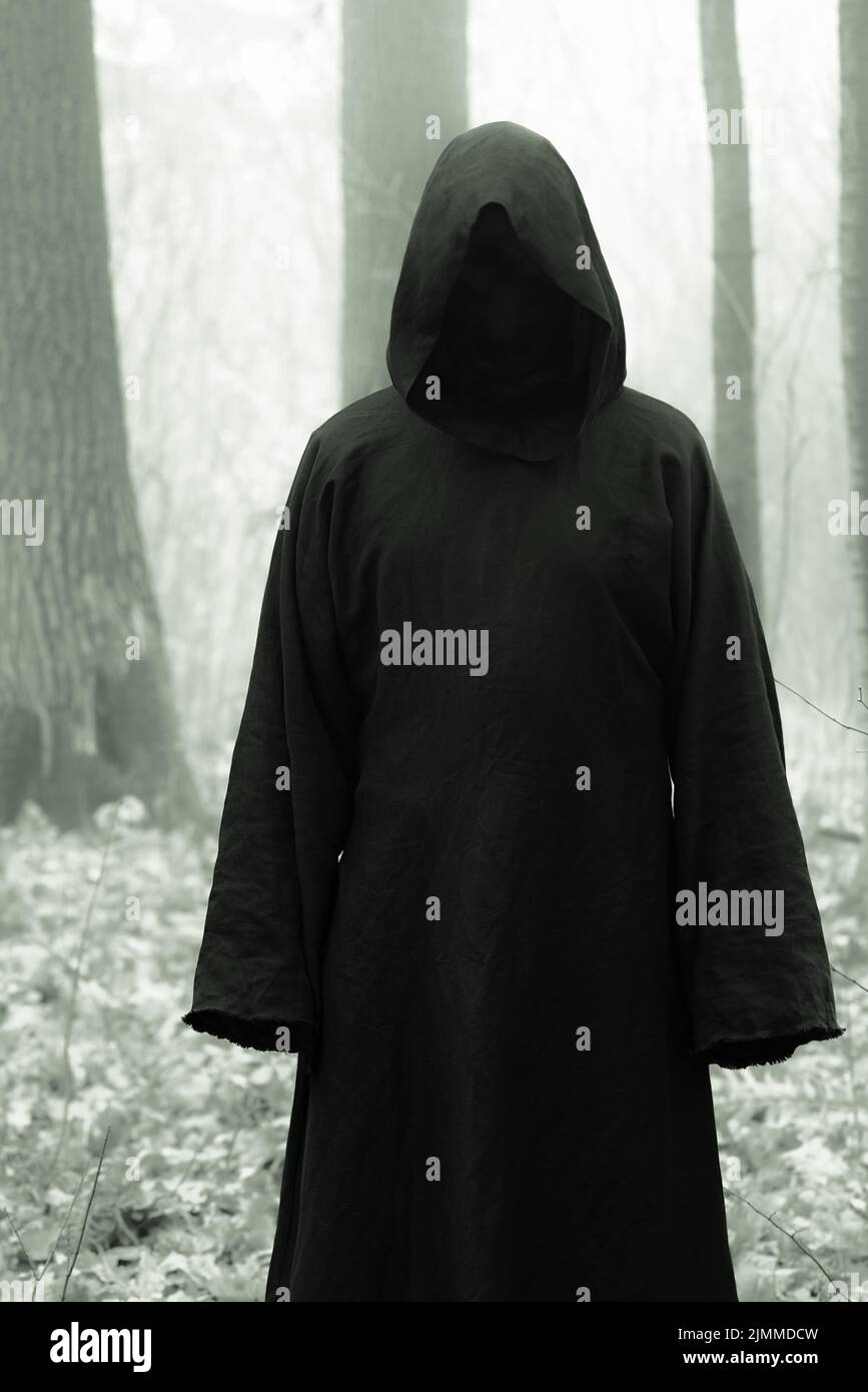 Death in a black hoodie mantle in forest mistery fog. Horror style fear ...