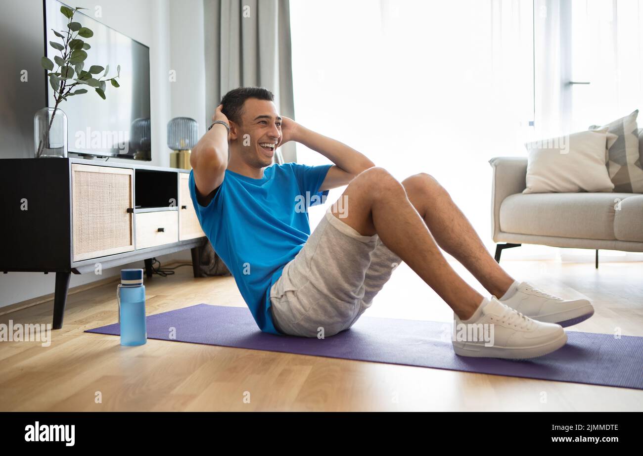 Young arab guy exercising on yoga mat, strengthening abs muscles at ...