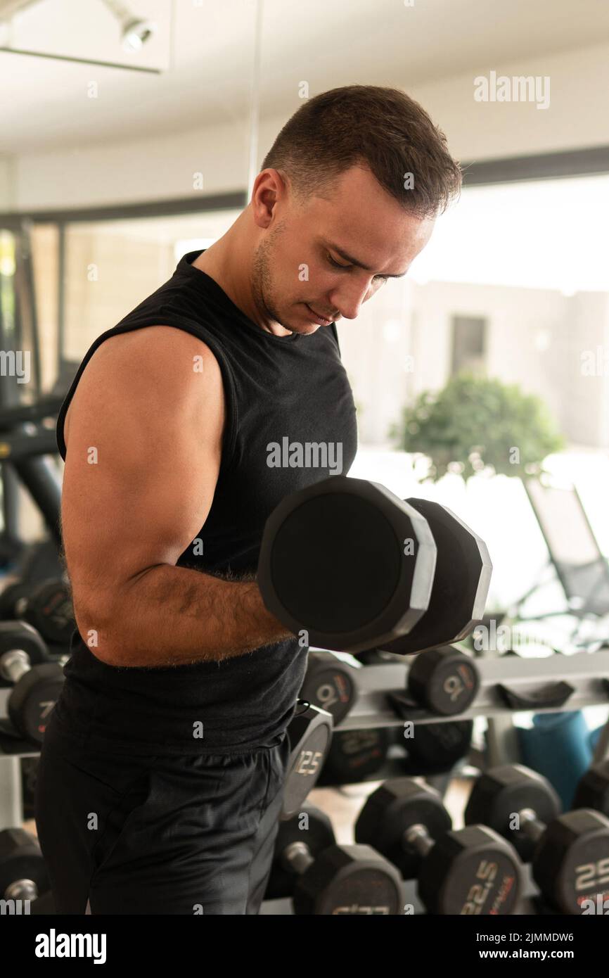 Athletic man working out with a dumbbells in the gym Stock Photo - Alamy