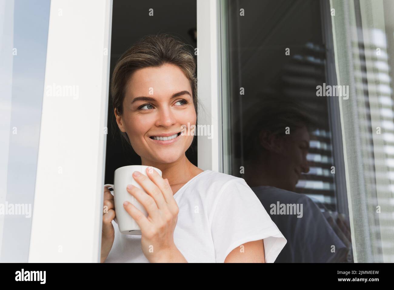 Beautiful woman with a cup of hot coffee looking into the window Stock ...