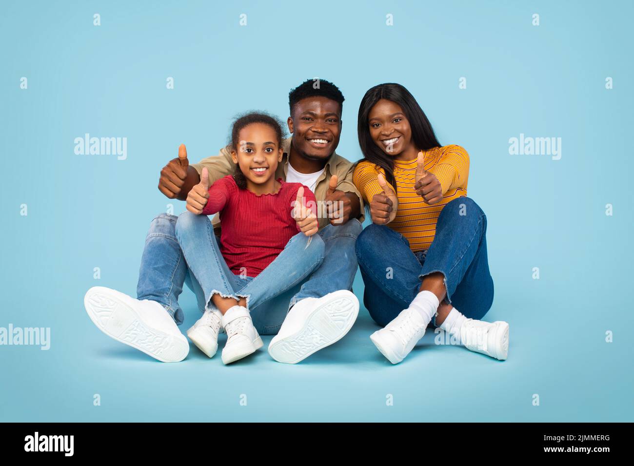 Excited black parents and daughter gesturing thumbs up, approving ...