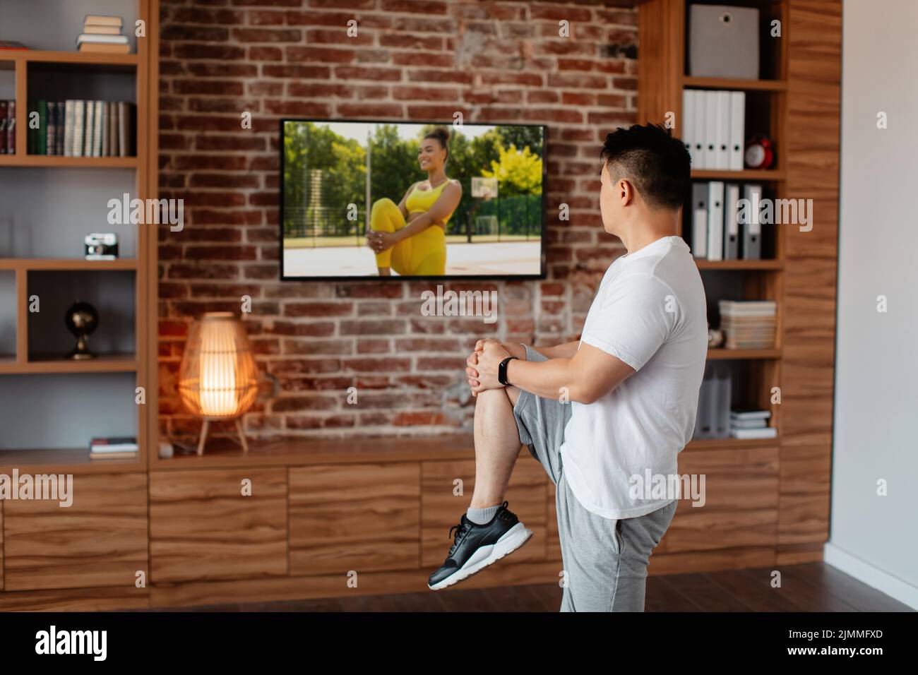 Active asian mature man exercising at home and watching fitness workout ...