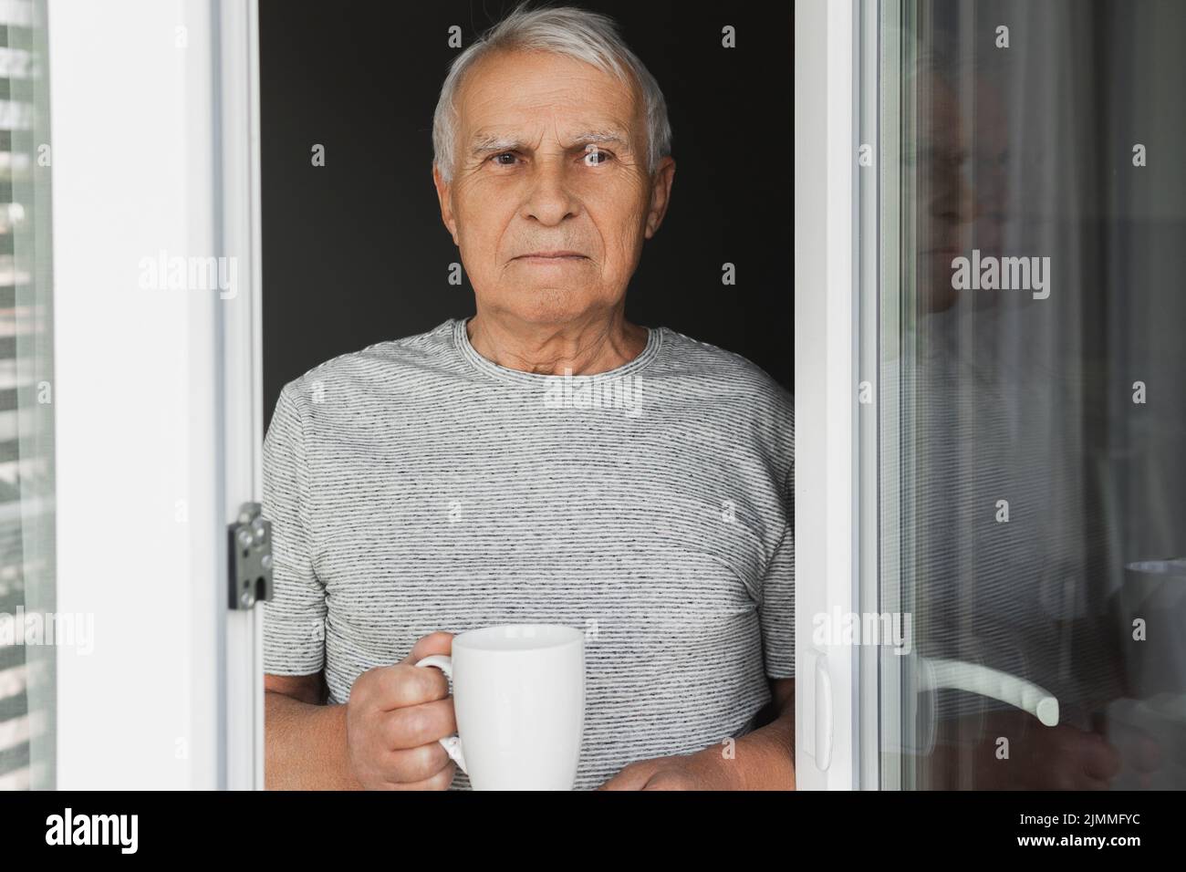 Elderly man with a cup of coffee looking into the window Stock Photo ...