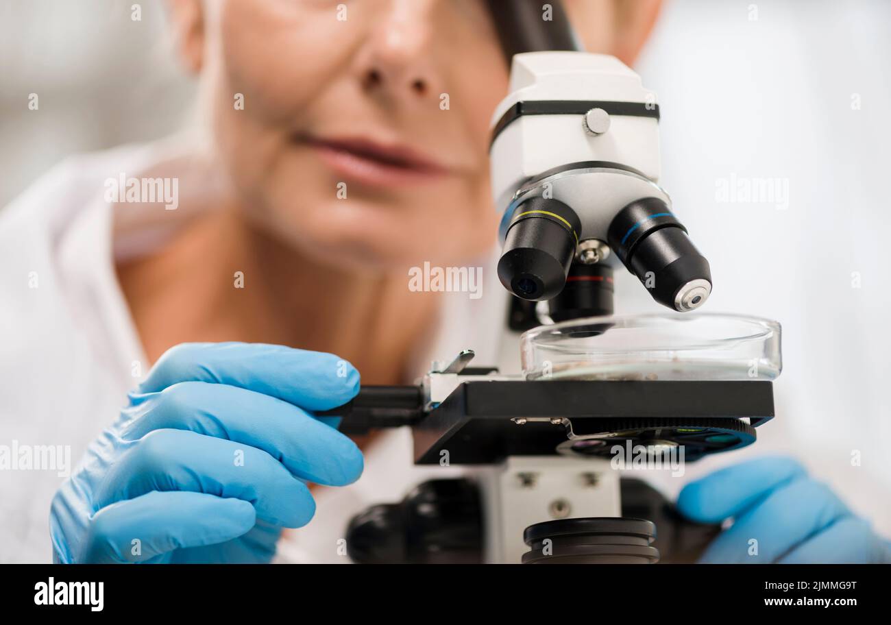 Defocused female scientist looking through microscope Stock Photo - Alamy