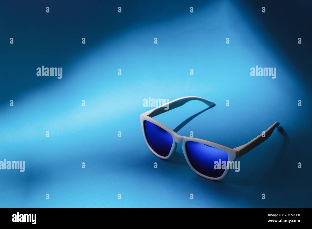 Blue sunglasses on blue background in a shadows scene with copy space ...