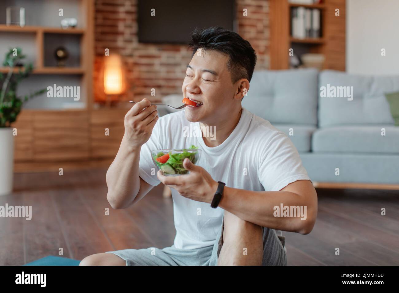 Fit asian middle aged man holding fork and bowl with fresh vegetable ...