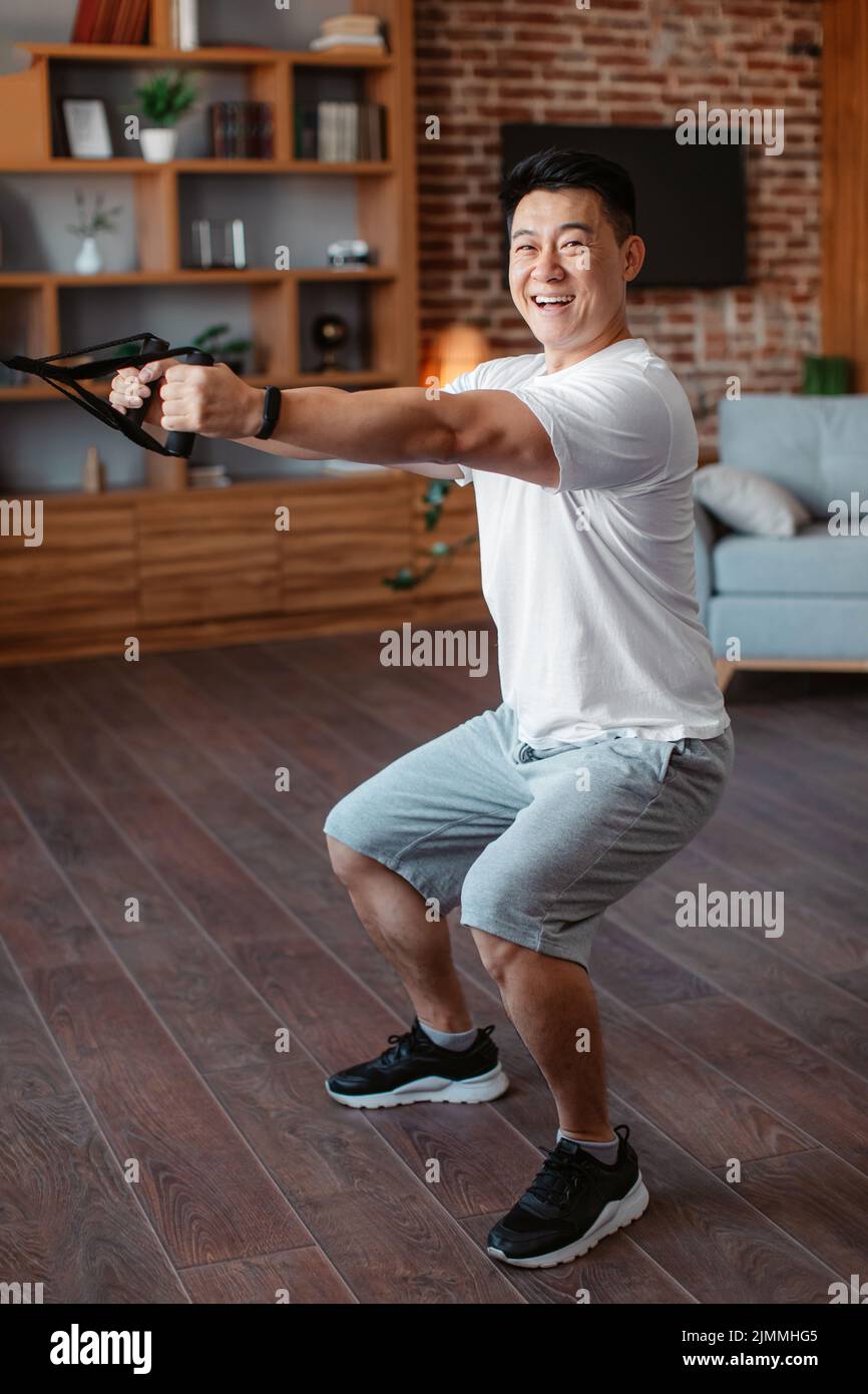Excited active asian man doing sport workout in living room, exercising ...