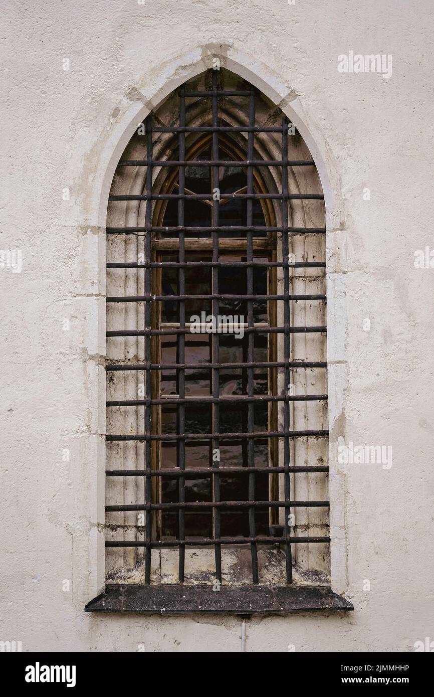 Old white stone wall with one arched grating window on the street in ...