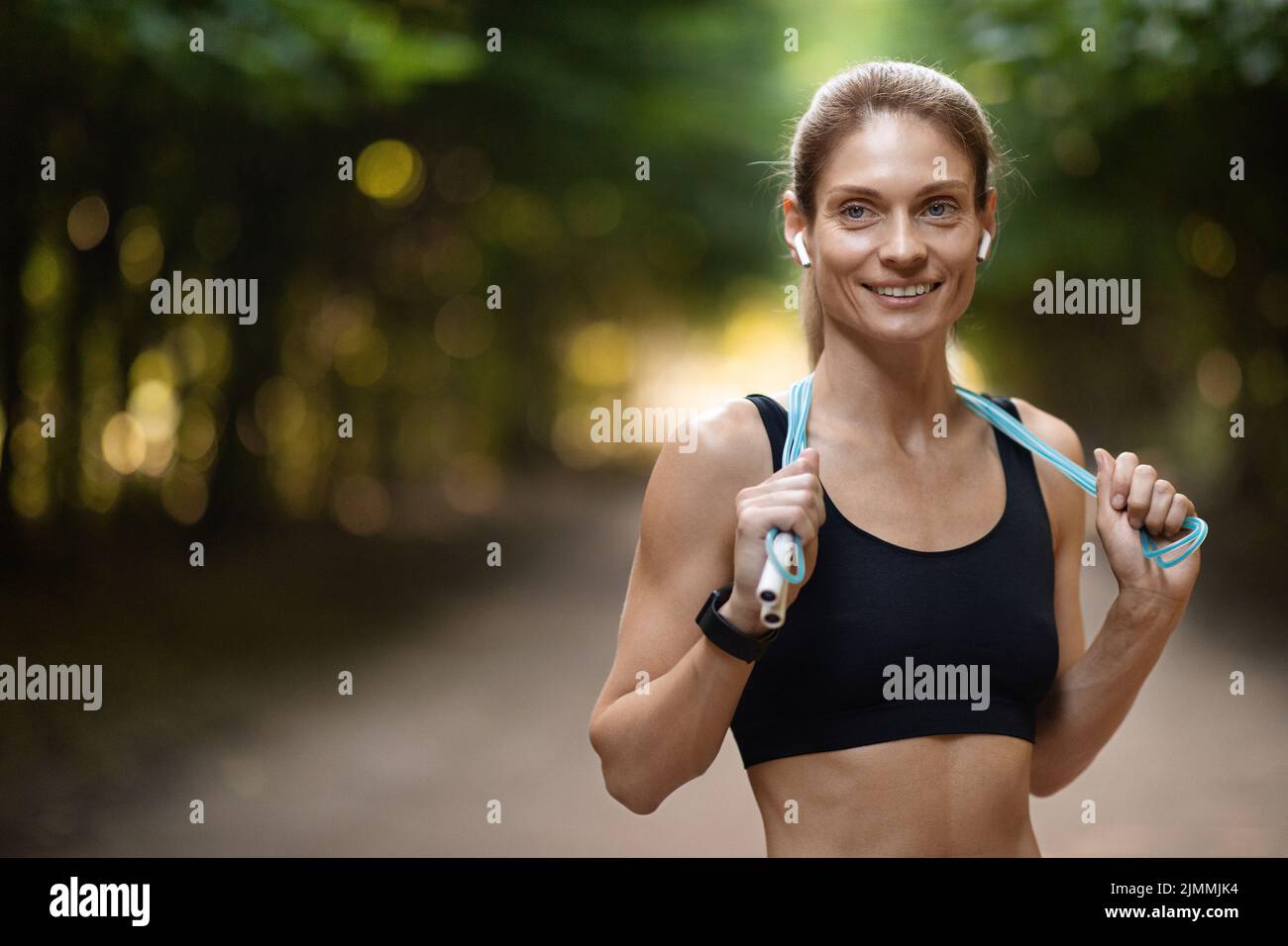 Cheerful woman doing workout outdoors, using skipping rope Stock Photo ...