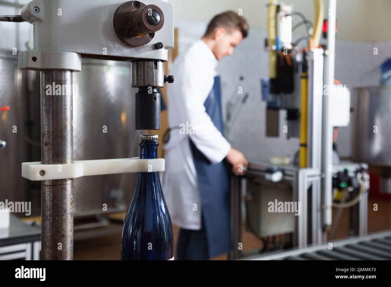 Male worker corking wine bottles with machine at sparkling wine factory ...