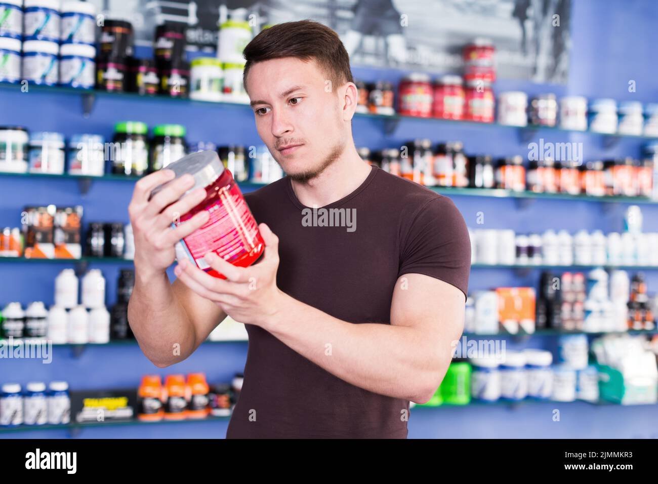 Young muscular guy reading content label, choosing sport nutrition ...