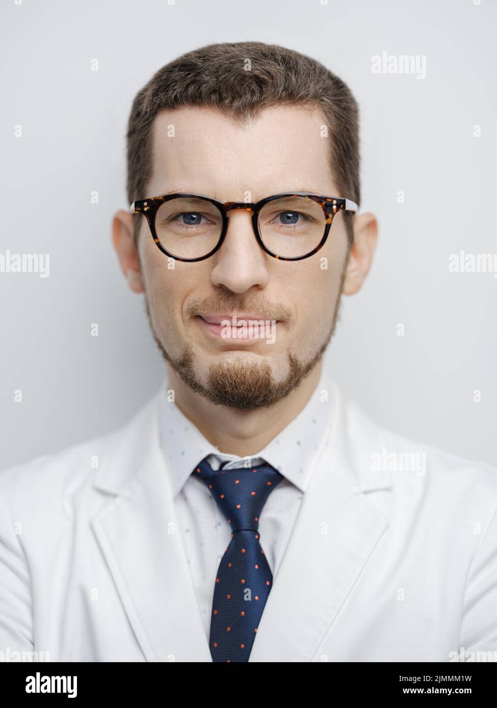 Portrait of happy young bearded male doctor smiling with eyeglasses ...