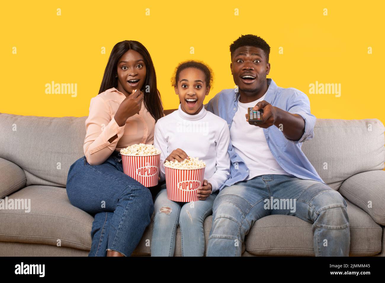 Shocked black parents and their daughter watching movie on TV, sitting ...