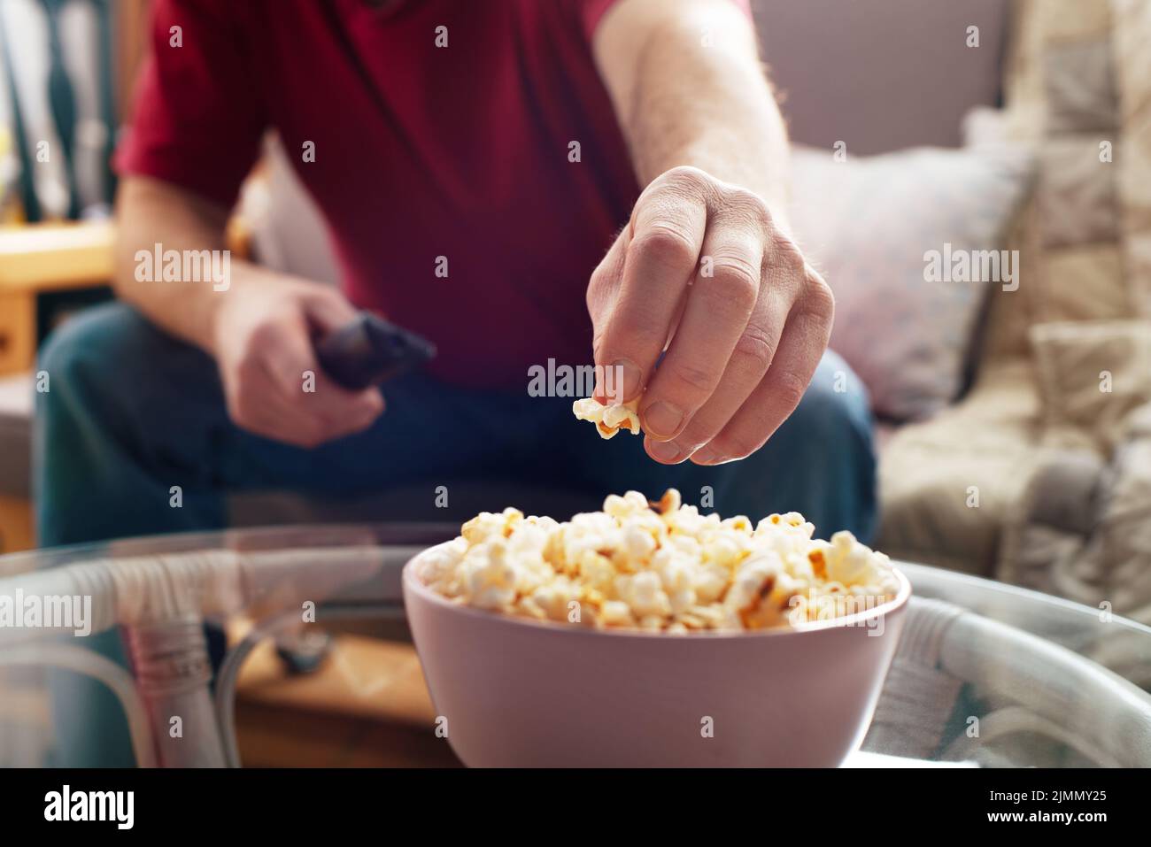 Caucasian man sitting on sofa with popcorn and tv remote Stock Photo ...