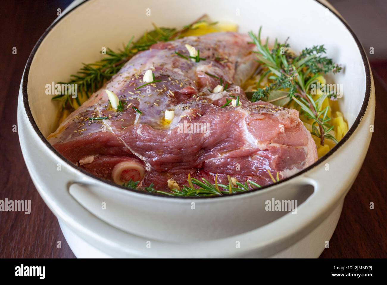 raw leg of lamb prepared to cook with sliced potatoes and provencal ...