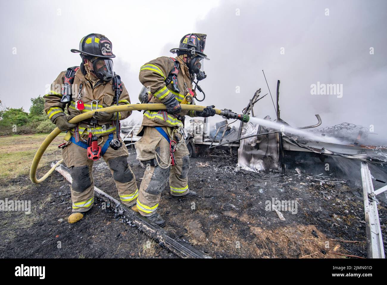 A two-man hose team wearing breathing apparatus hoses down the remains ...