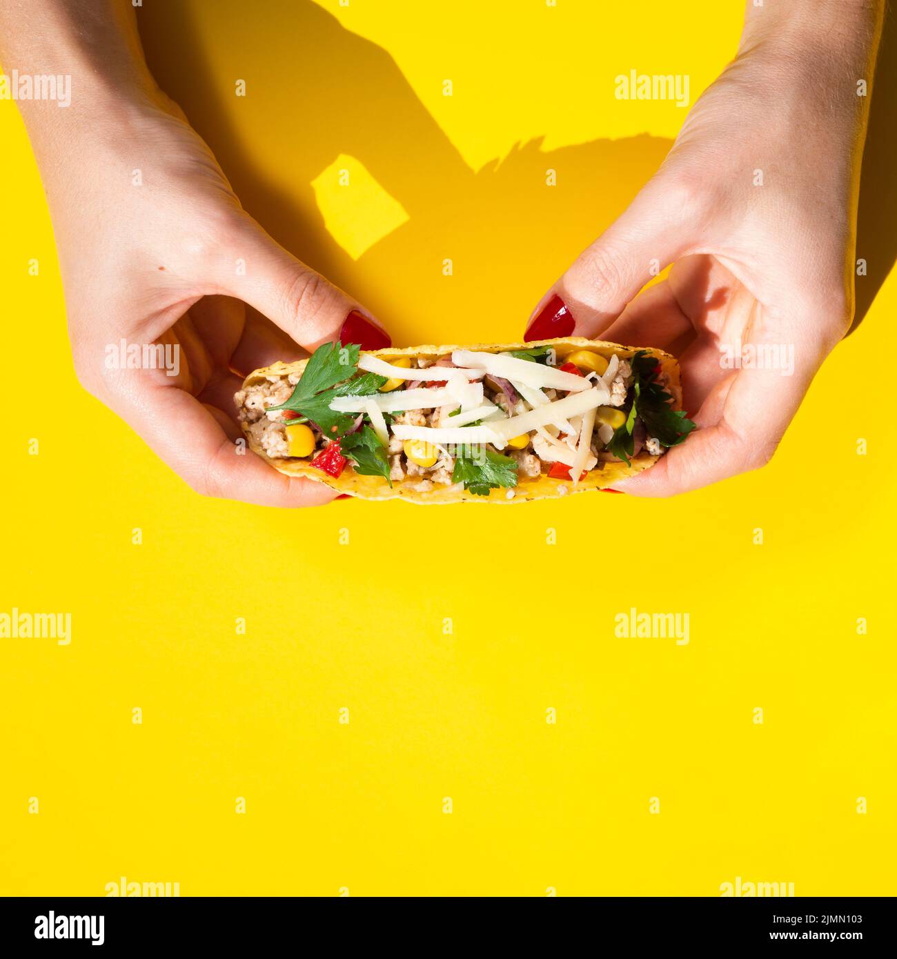 Close up hands holding taco with yellow background Stock Photo - Alamy