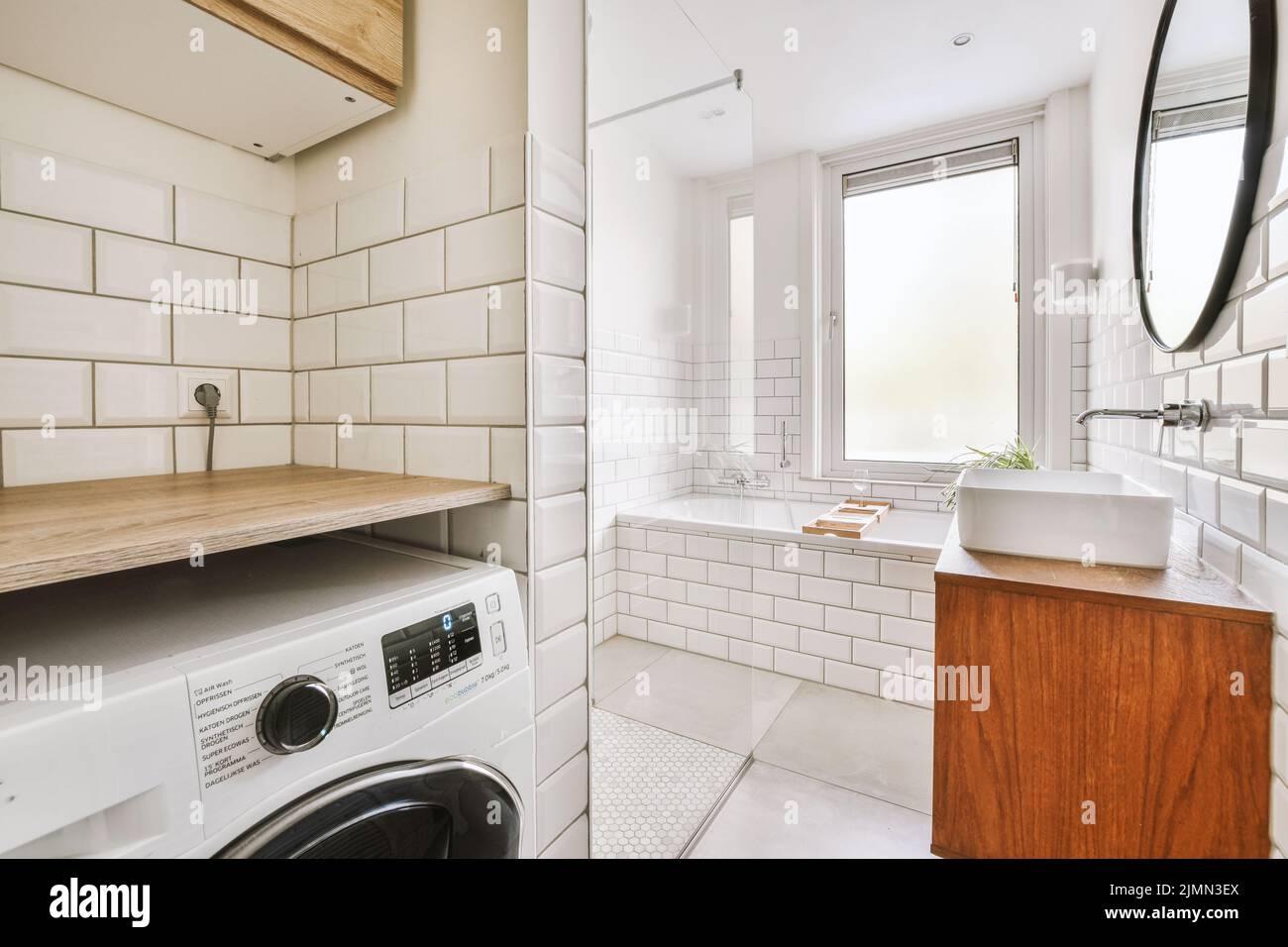 Sinks with mirrors and clean bathtub,washing machine located near ...