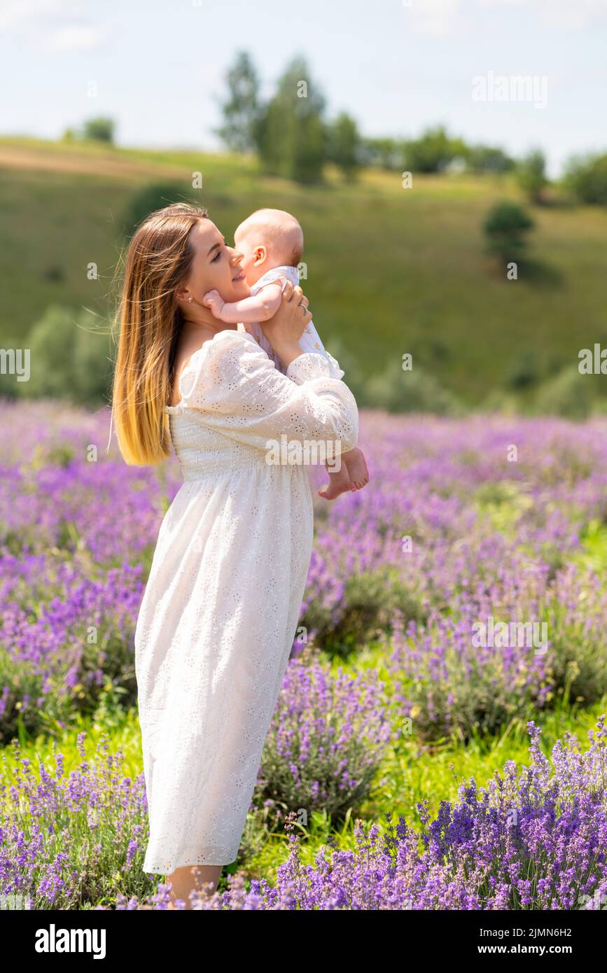 Happy loving young mother cuddling her little baby in her arms as she ...