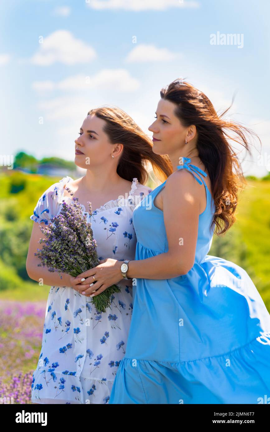 Two women friends posing together on a windy summer day outdoors in ...