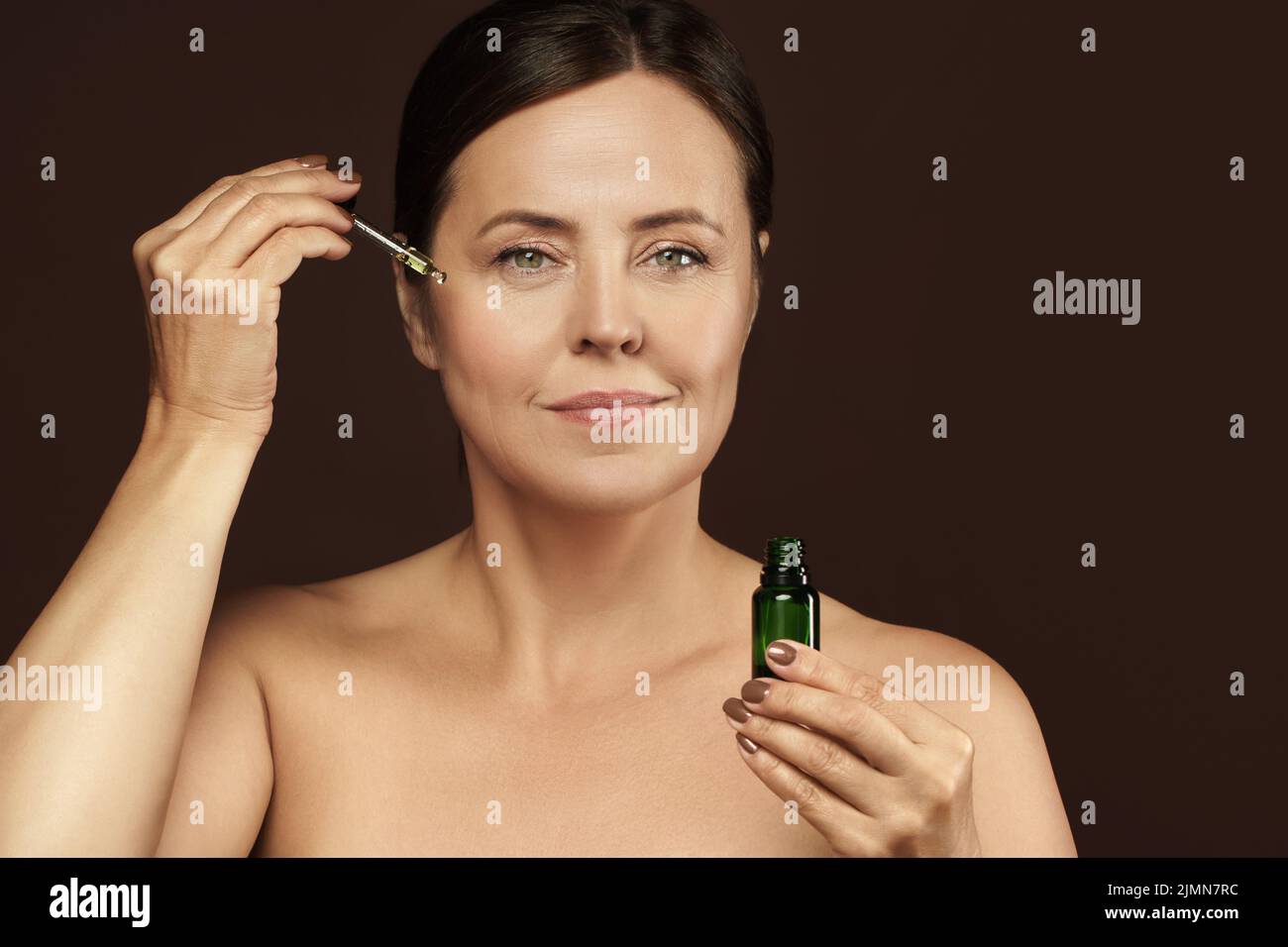 Beautiful Middle Aged Woman Holding Bottle With Cosmetic Oil Or Serum