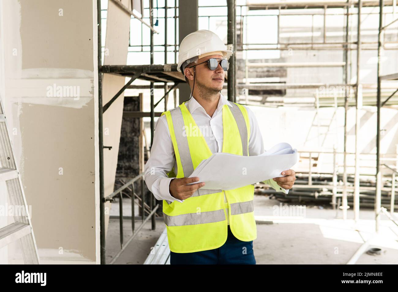 Man architect wearing safety vest with a blueprints on a construction site Stock Photo - Alamy