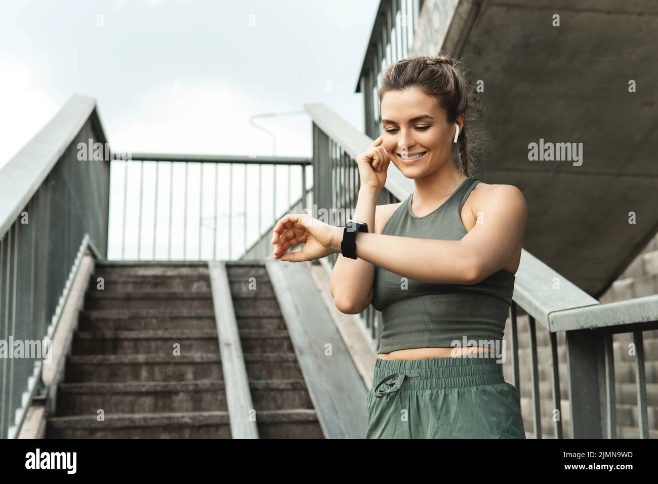 Athletic woman using smartwatch during her fitness workout on city ...