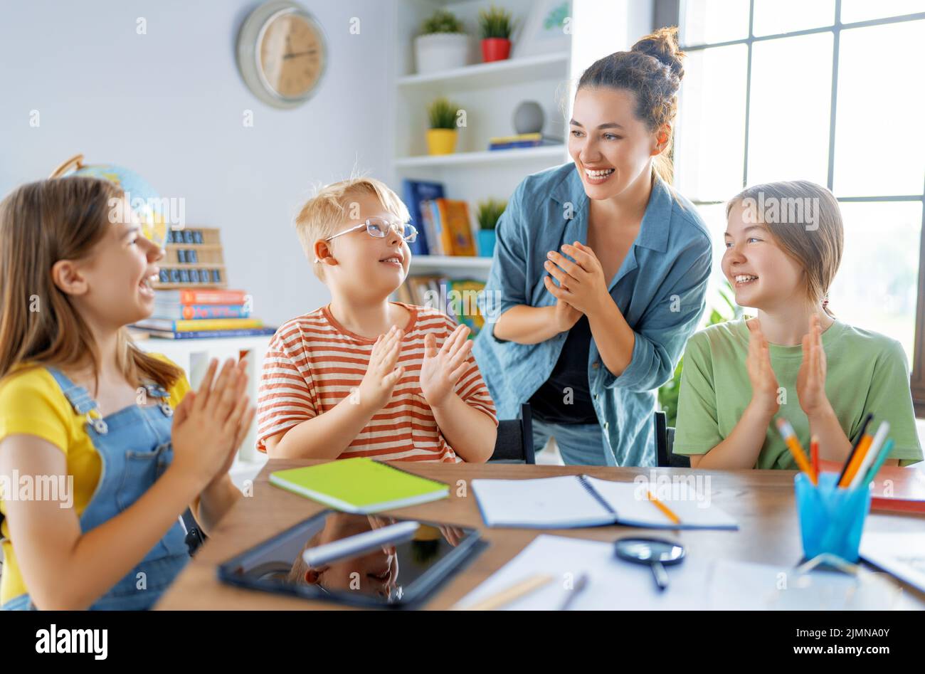 Happy kids and teacher at school. Woman and children are talking in the ...