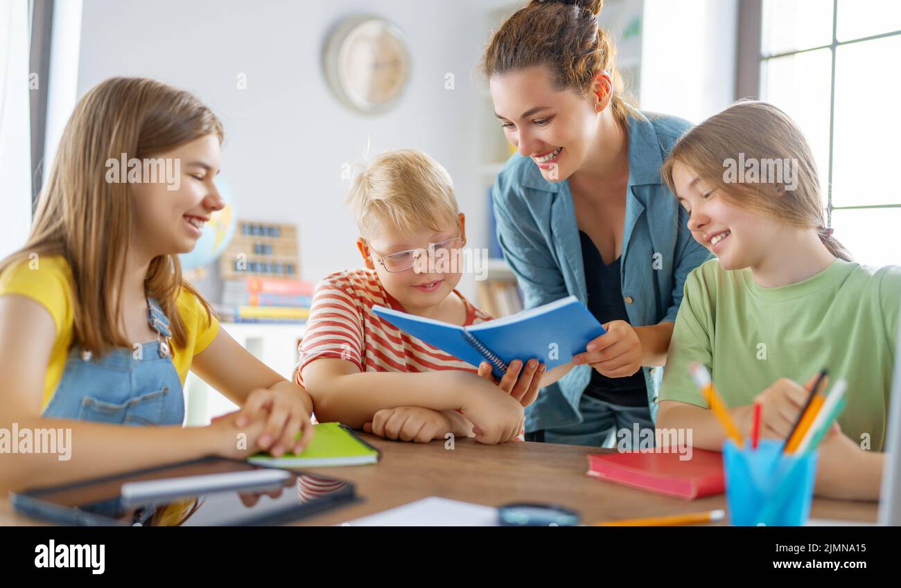 Happy kids and teacher at school. Woman and children are talking in the ...