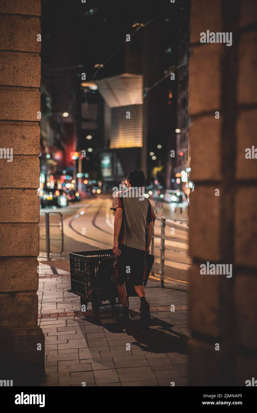 A vertical shot of a young delivery man working at late night and ...