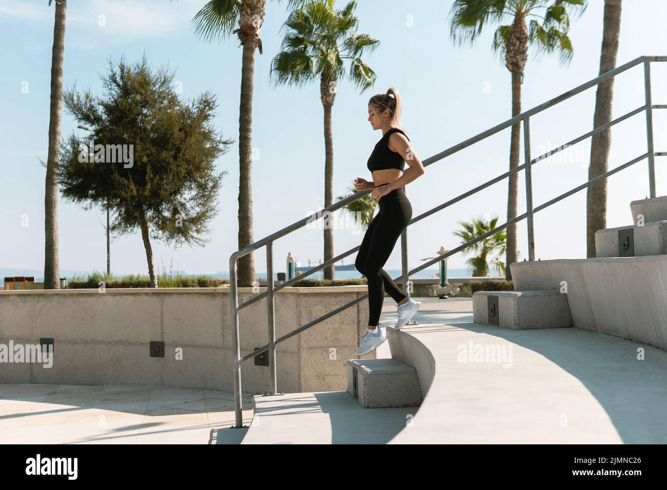 Athletic woman is running on concrete stairs during her summer workout ...