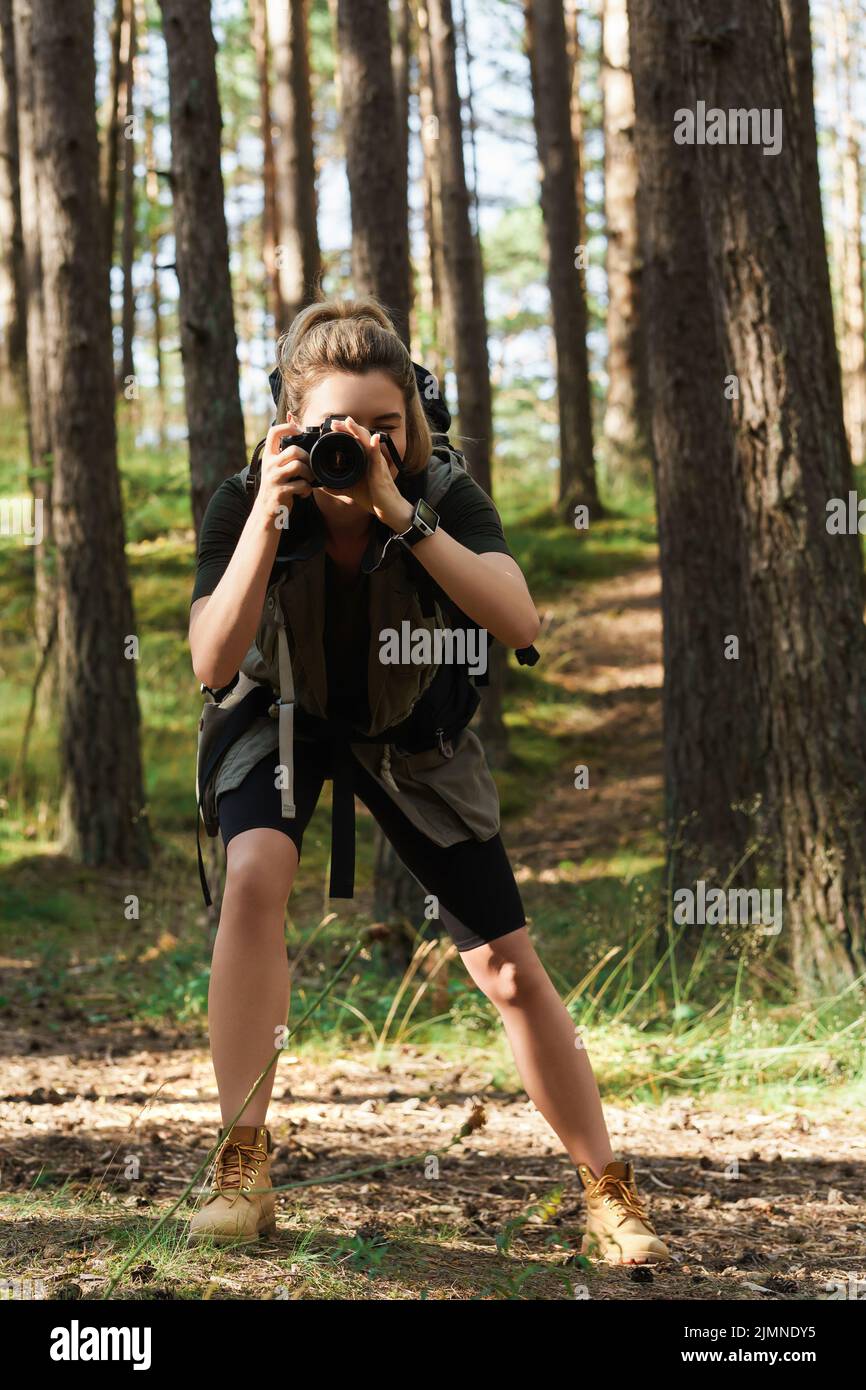 Hiker taking photos using modern mirrorless camera in green forest ...