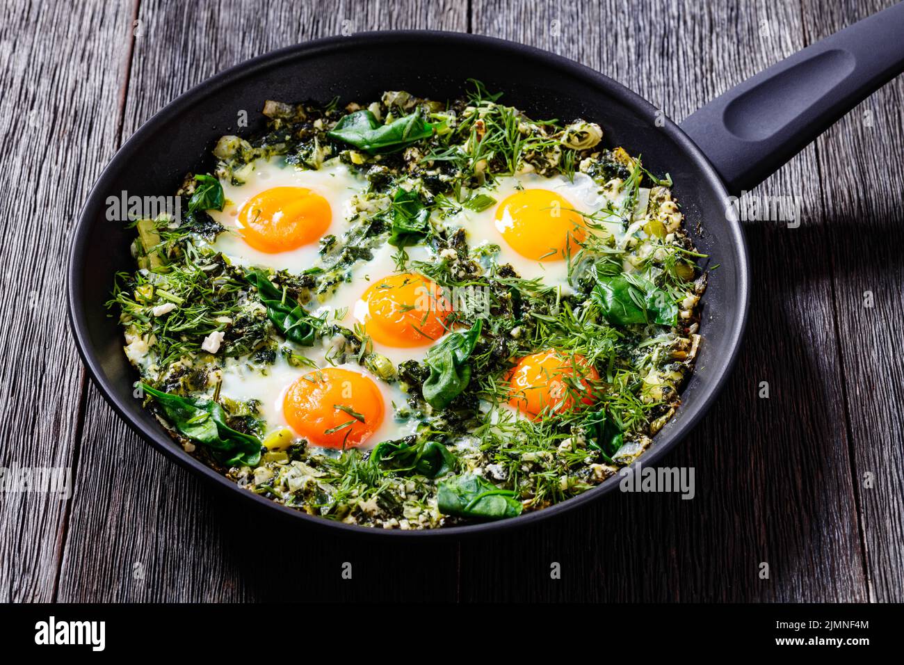 green shakshuka of spinach, leeks, green onion, crumbled feta cheese in ...