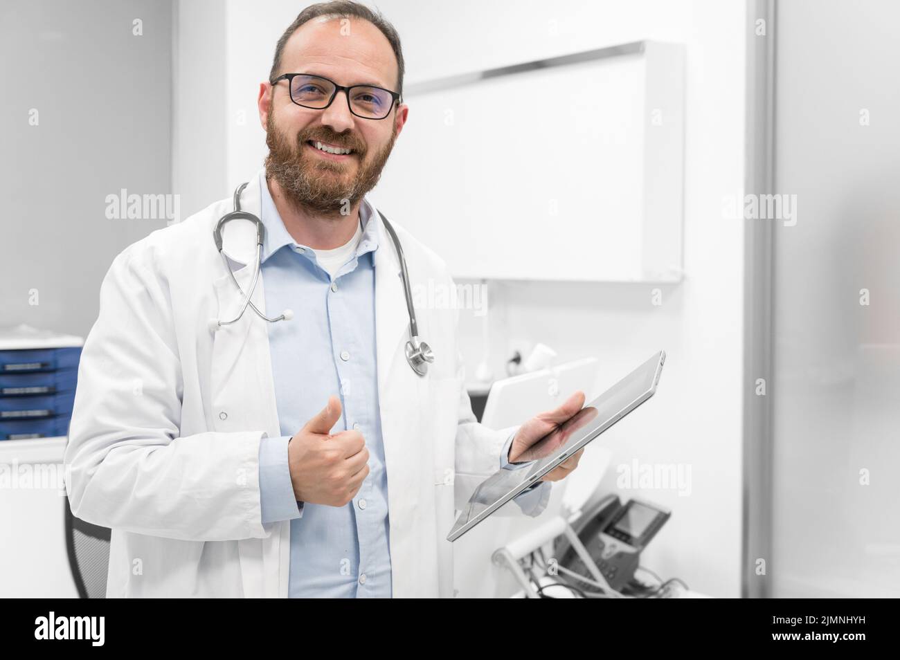 Friendly male doctor smiling and giving thumb up sign Stock Photo - Alamy