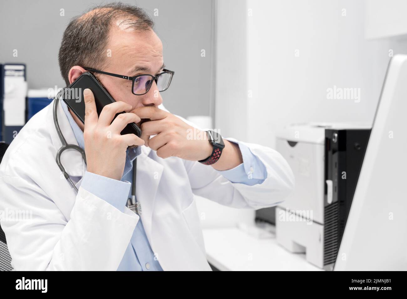 Doctor looking worried a desktop computer screen, checking the results ...