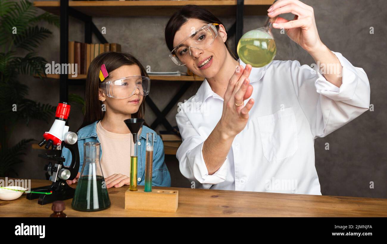 Girl teacher doing science experiments with microscope Stock Photo - Alamy