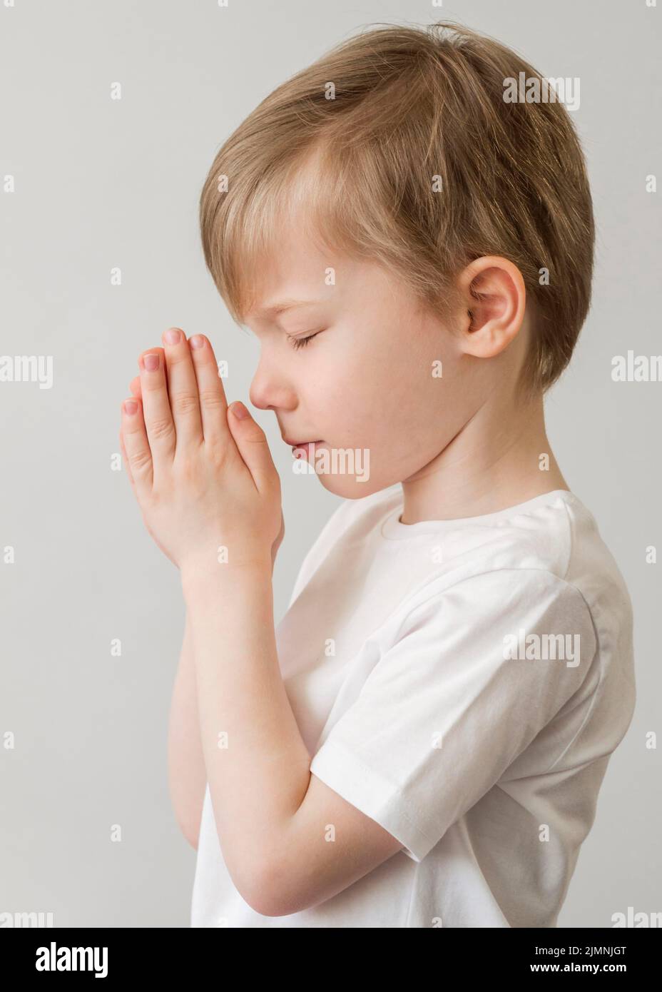 Side view little boy praying Stock Photo - Alamy