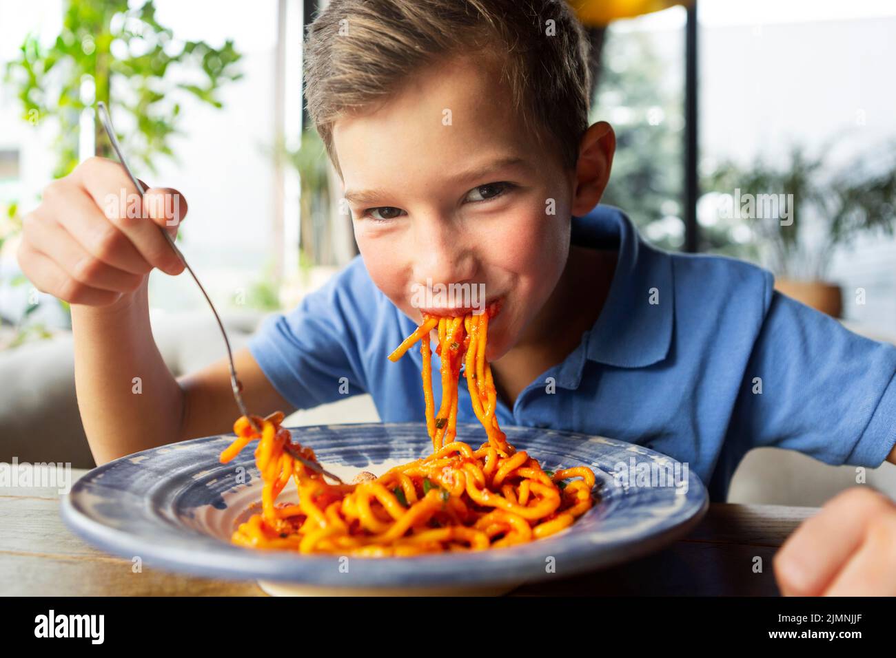 Medium shot smiley boy eating spaghetti Stock Photo - Alamy