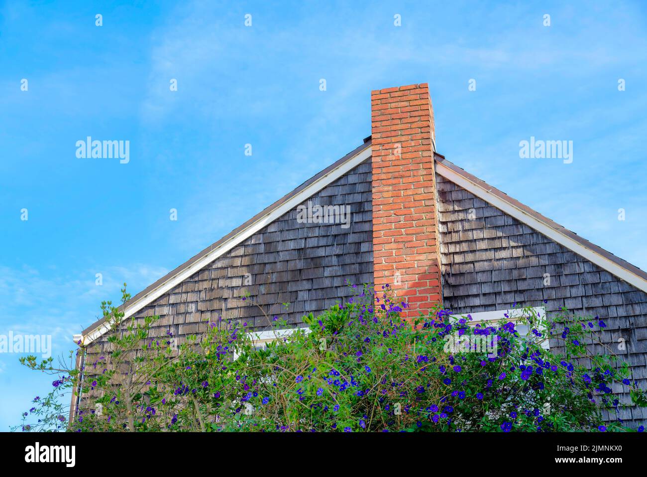 Flowering plants outside a house with wood shingles sidings and chimney ...