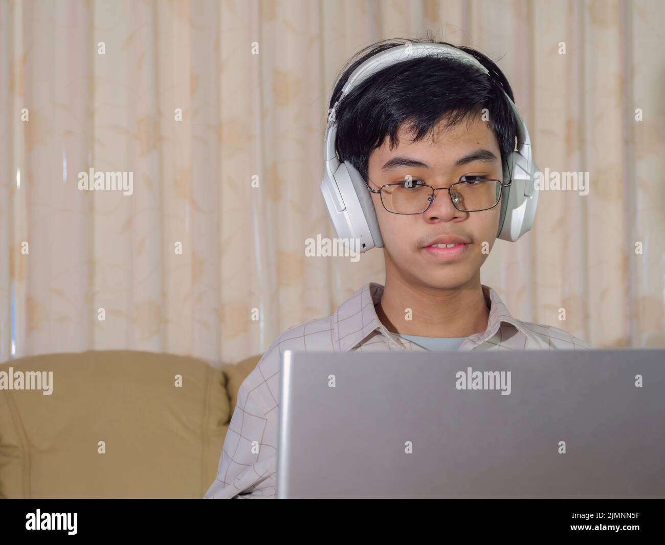 Preteen schoolboy wearing headphone to learning online watching class ...