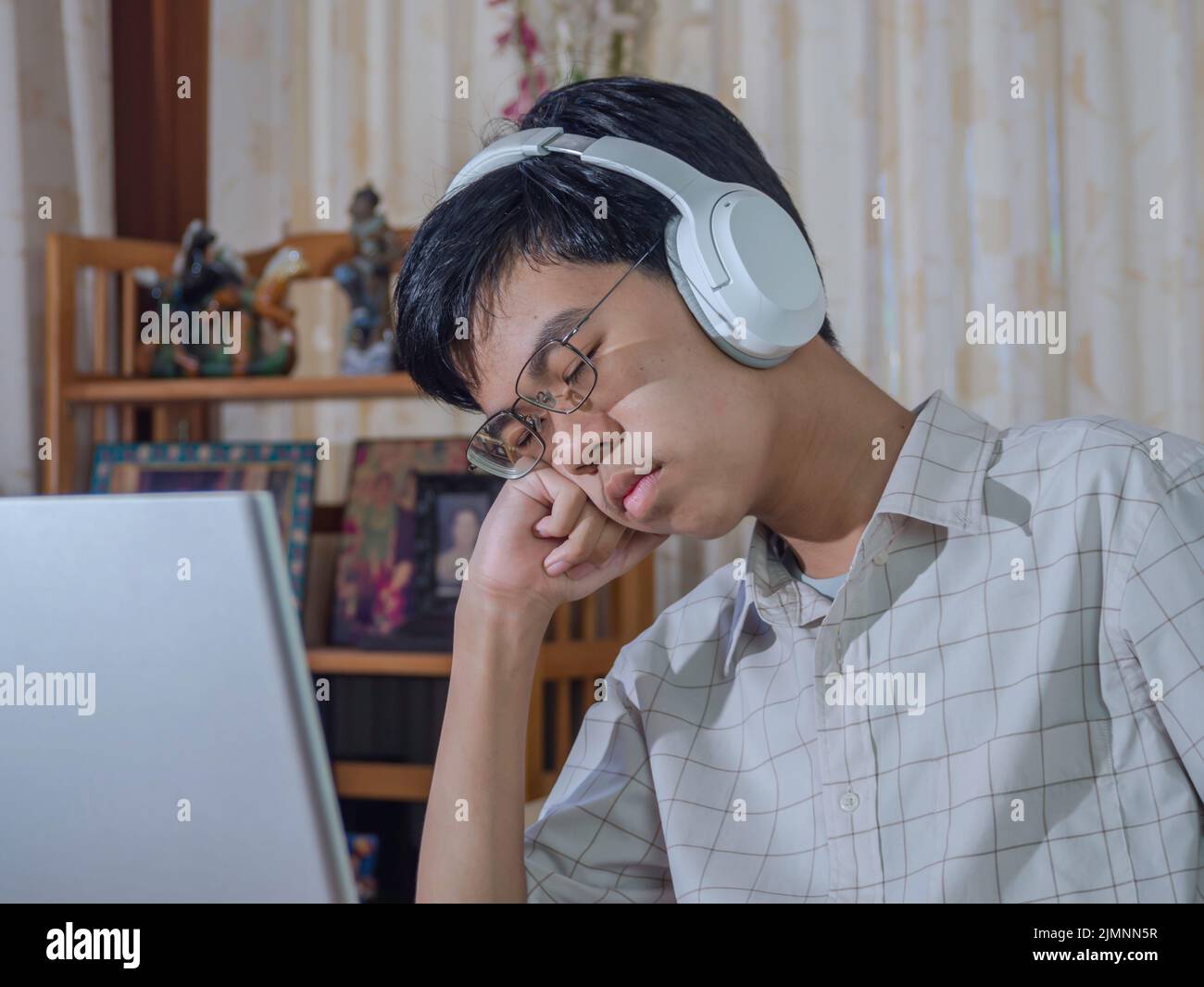 Bored sleepy student wearing headphone tired of learning doing homework ...