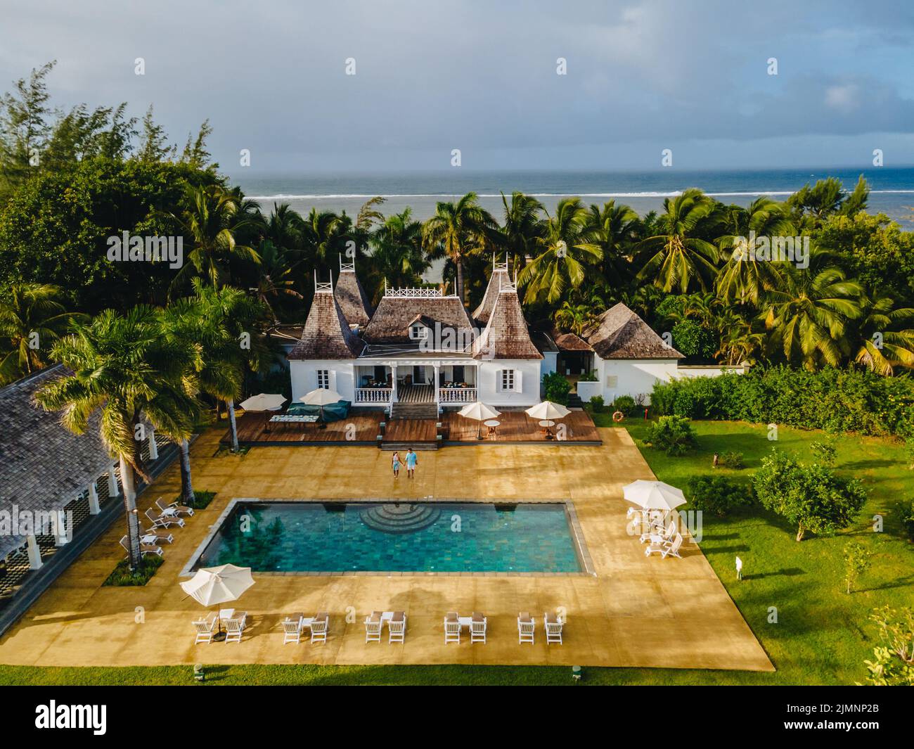 Old planttation house with swimming pool and beach chairs by the ocean ...