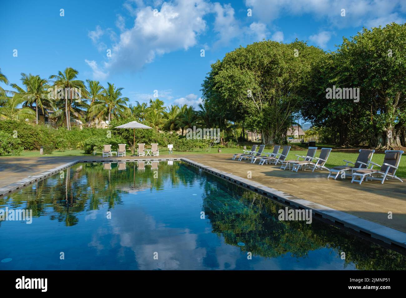 Swimming pool with beach chairs and lunch table at a luxury resort ...