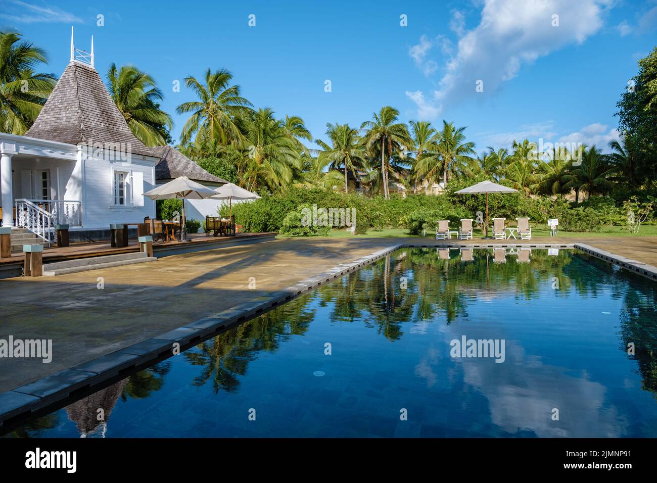 Swimming pool with beach chairs and lunch table at a luxury resort ...