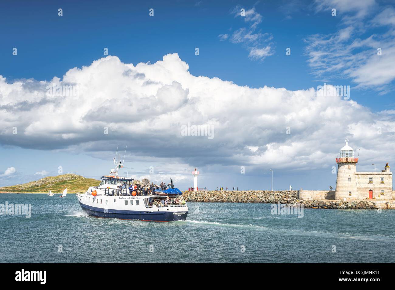 Group of people on a tour boat in Howth marina with Howth Lighthouse ...