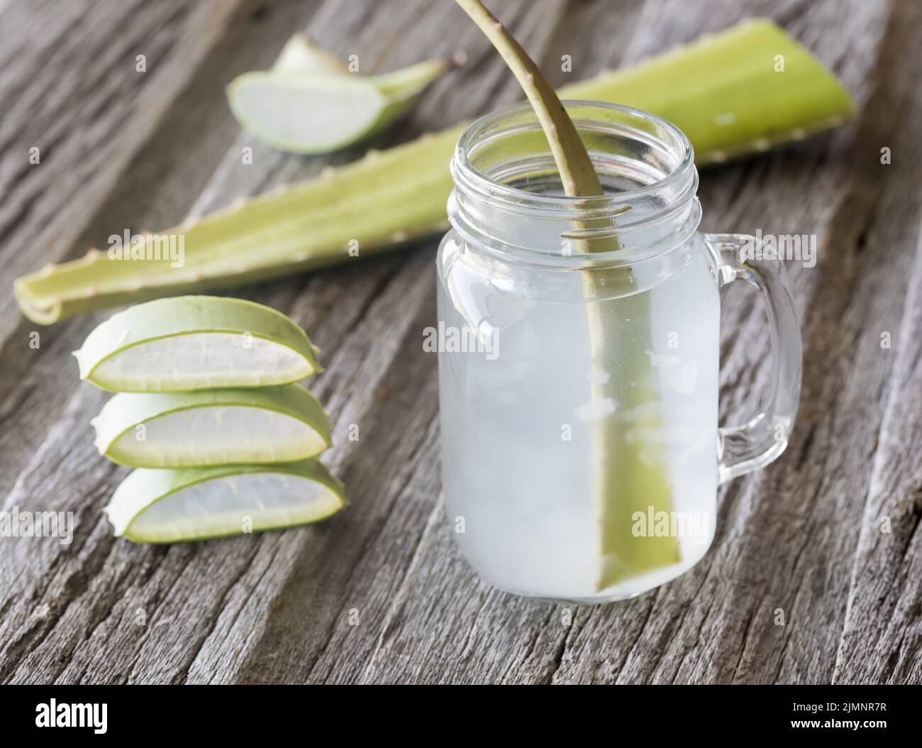 A jar filled with aloe vera juice beside slices of aloe Stock Photo - Alamy