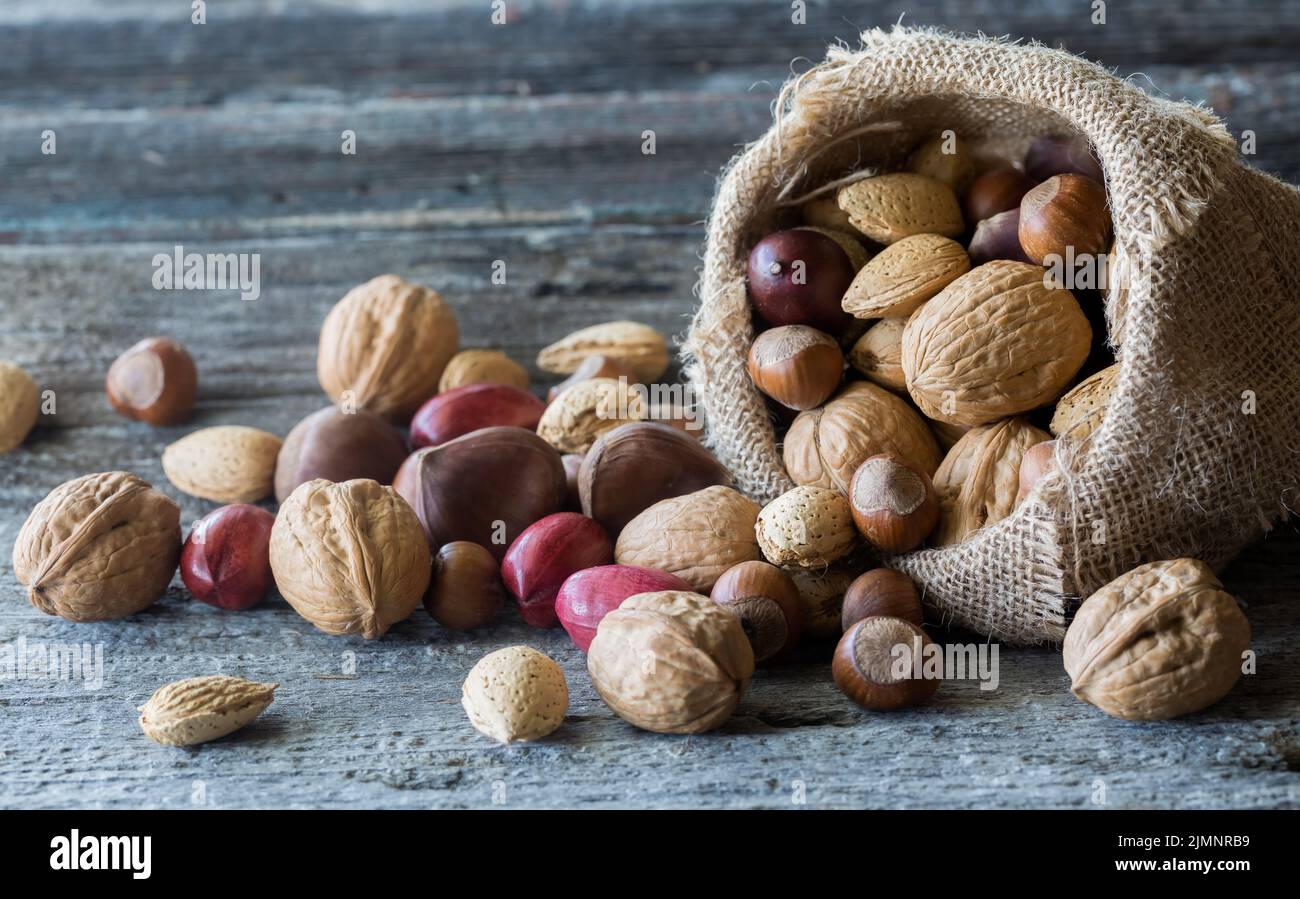 Mixed whole nuts spilling out of a burlap bag Stock Photo - Alamy
