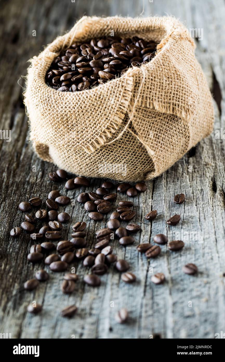 A burlap sack filled with coffee beans wth some spilled out in front ...