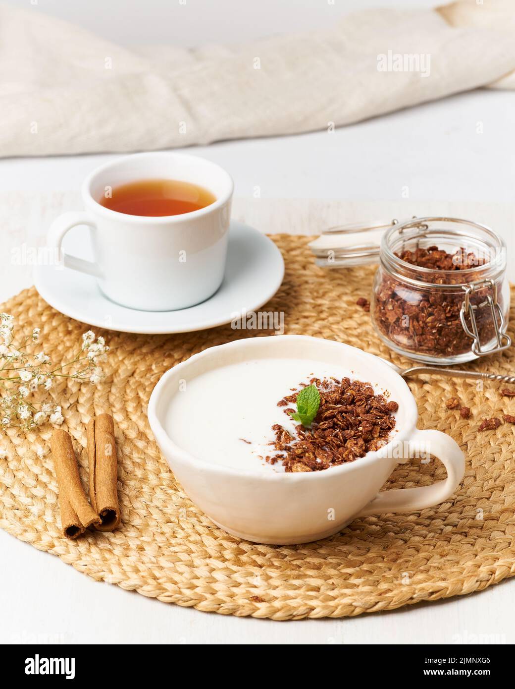 Yogurt with chocolate granola in cup, breakfast with tea on beige ...