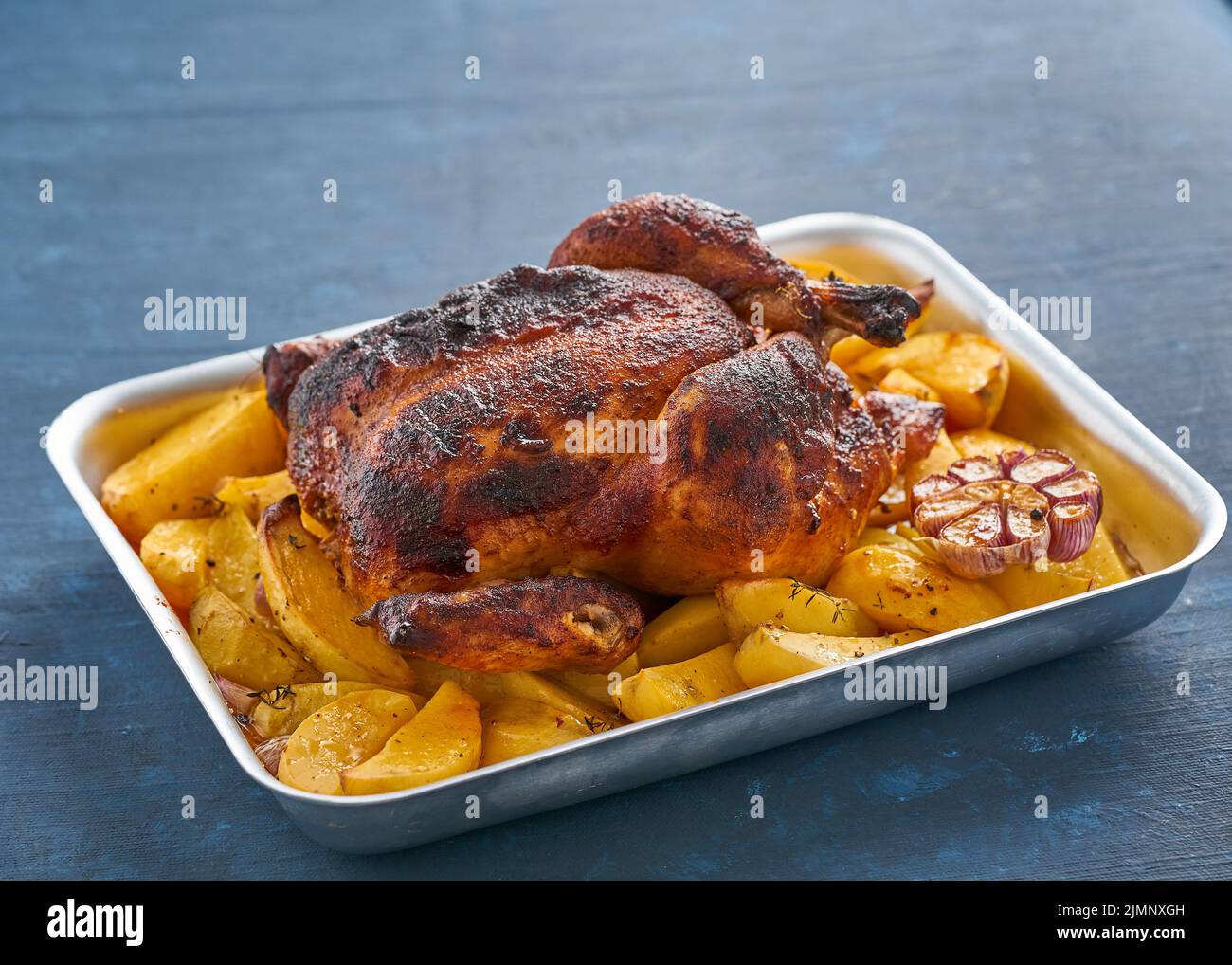 Baked whole chicken in blue casserole on dark blue table, roasted meat ...